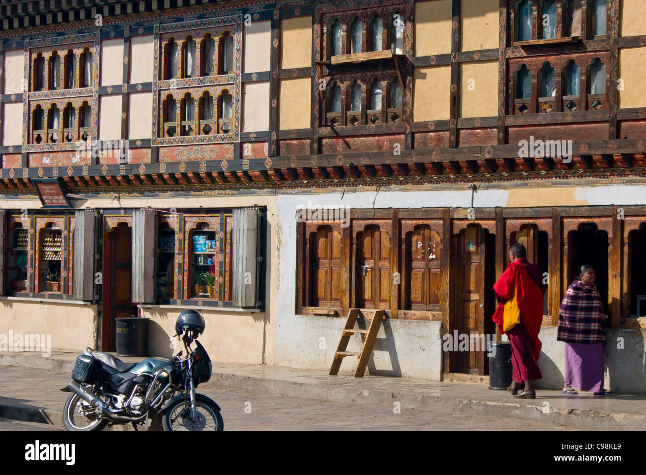 Shop fronts in Paro with ladder and a Monk walking by Stock Photo - Alamy