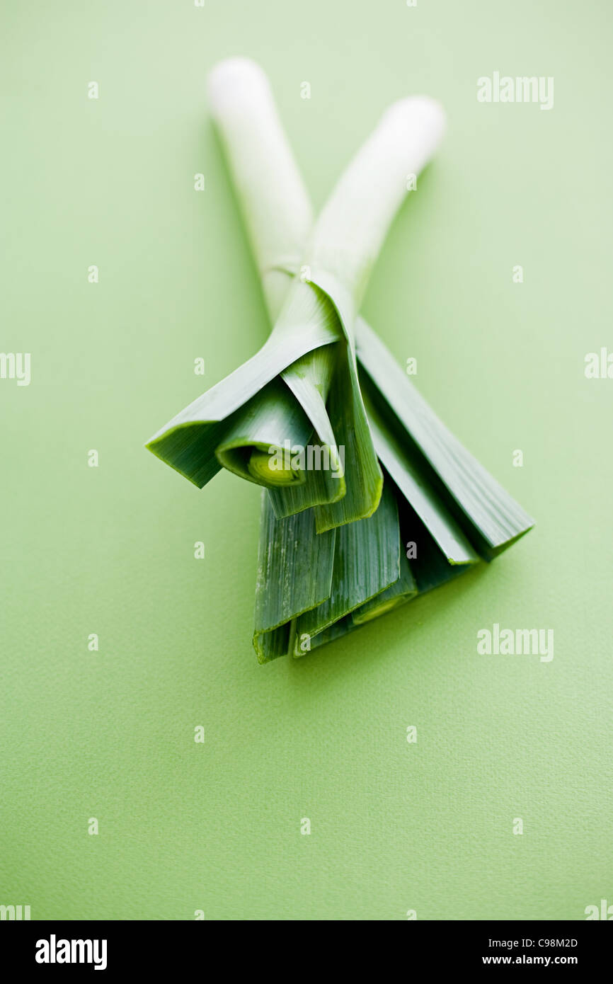 Leeks against green background Stock Photo - Alamy