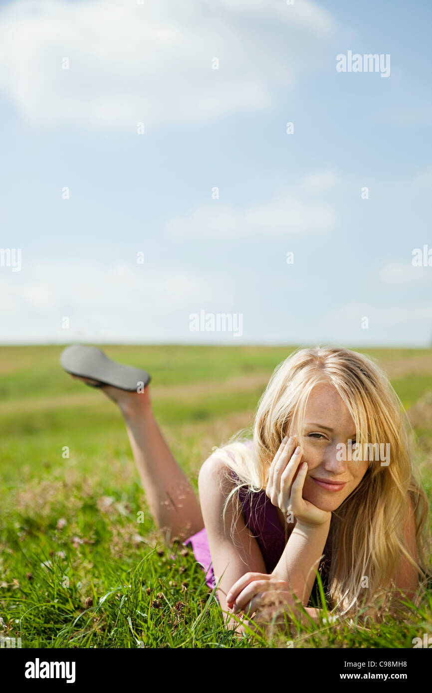 Young woman lying on her front field, smiling Stock Photo - Alamy