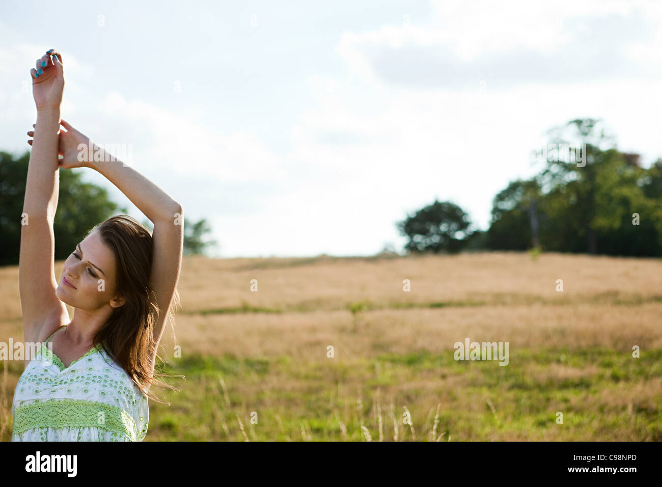 Young woman stretching field Stock Photo - Alamy