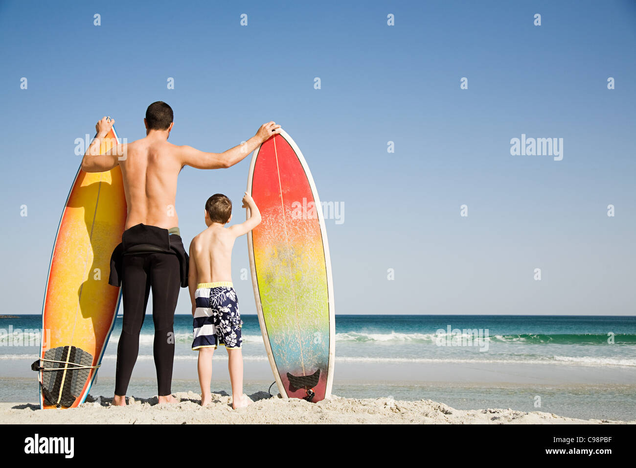 Father and son with surfboards gazing to sea Stock Photo - Alamy