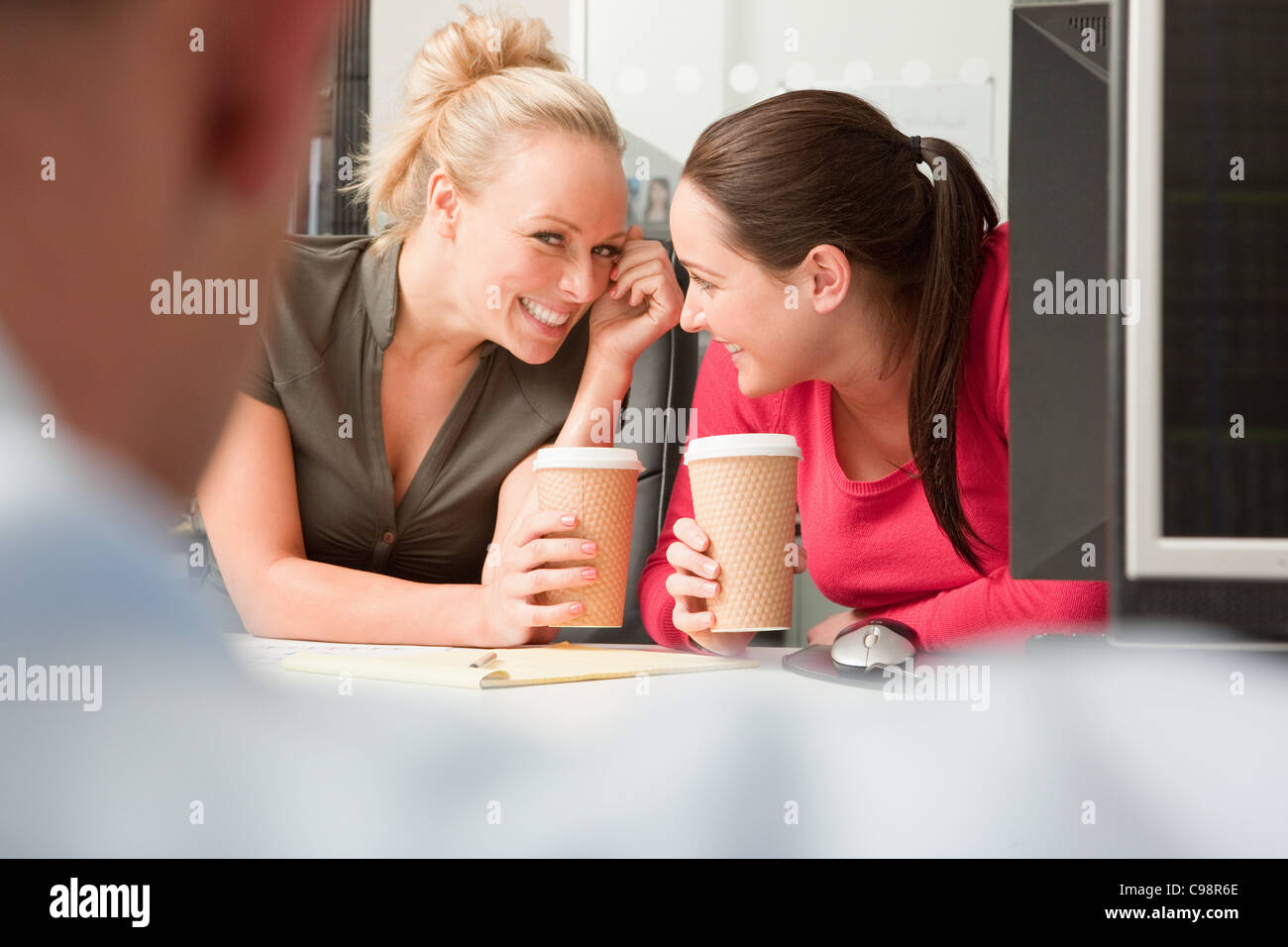 Female colleagues sharing secret about male colleague Stock Photo - Alamy