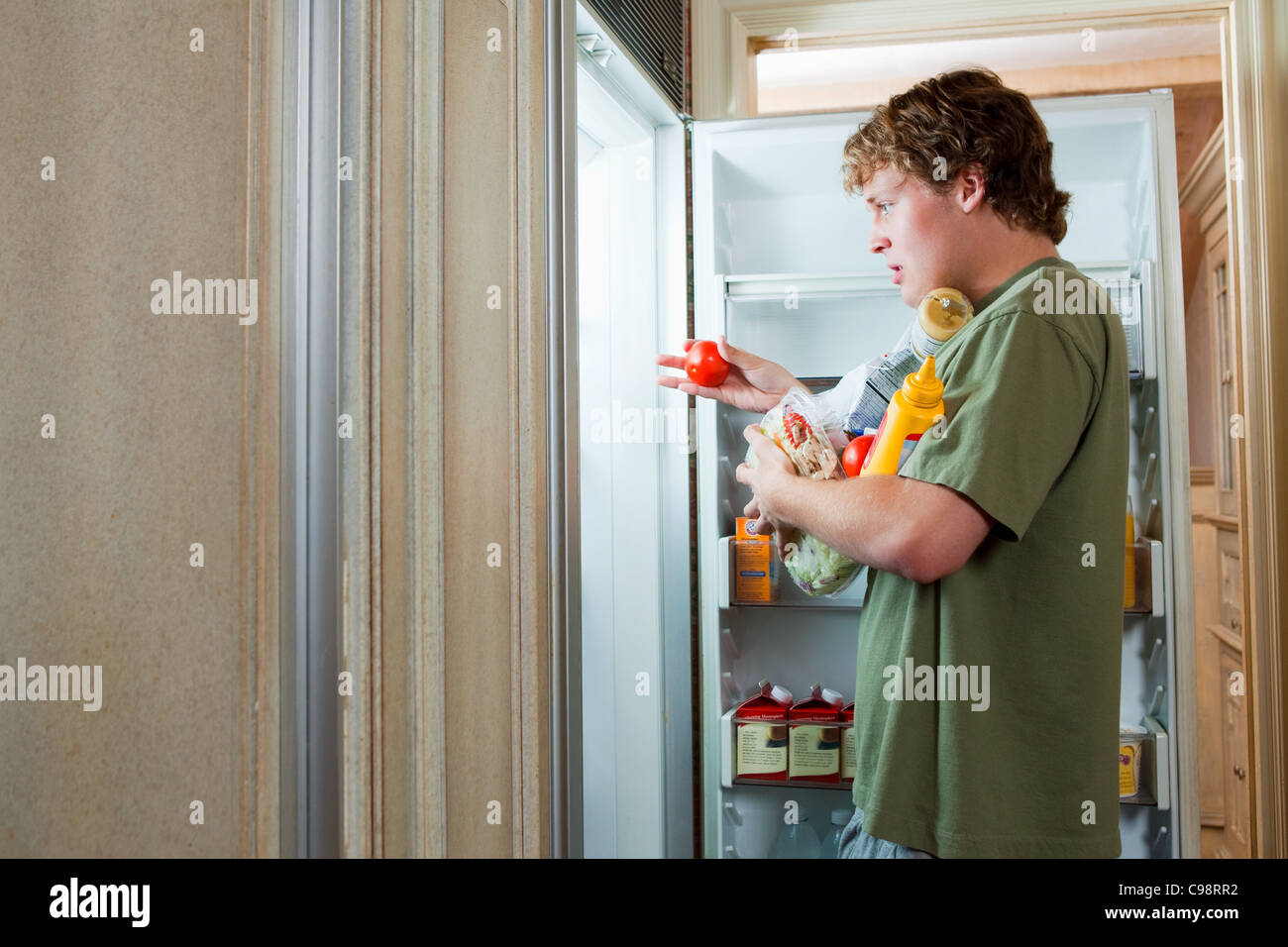 Teenage boy taking food from fridge Stock Photo - Alamy