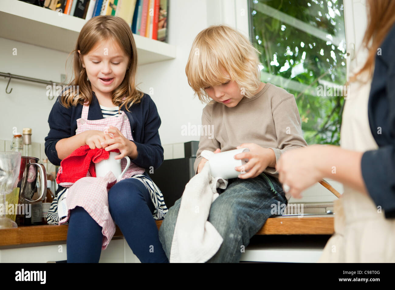 Siblings drying cups on kitchen counter Stock Photo - Alamy