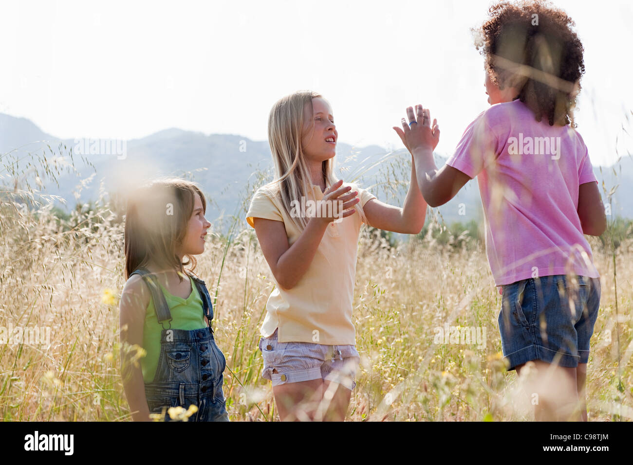 Girls playing pat a cake in field Stock Photo - Alamy