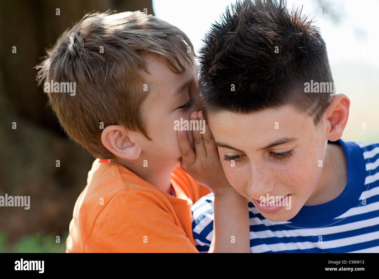 Boy whispering to firiend Stock Photo - Alamy
