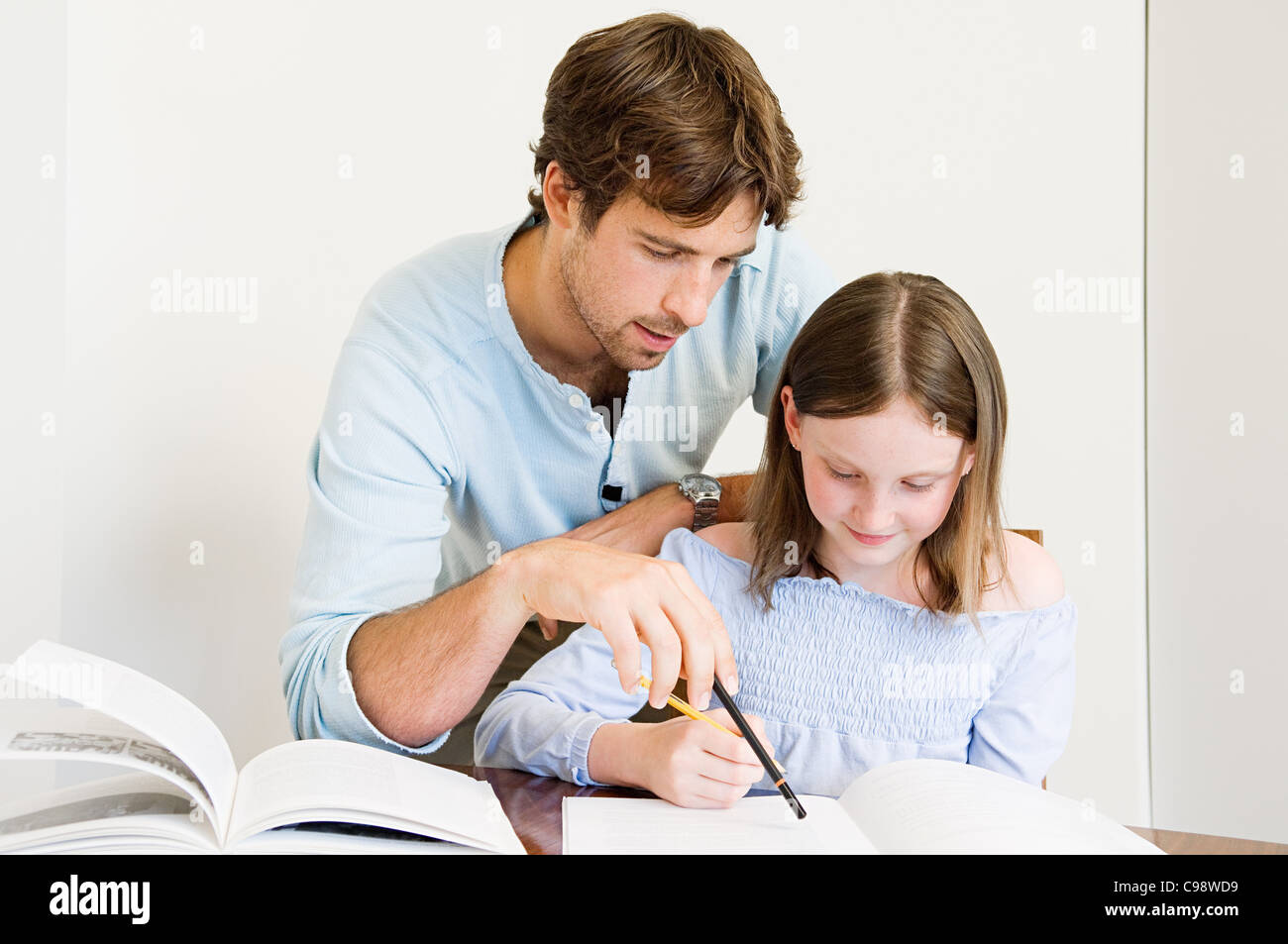 Young man helping daughter with homework Stock Photo - Alamy