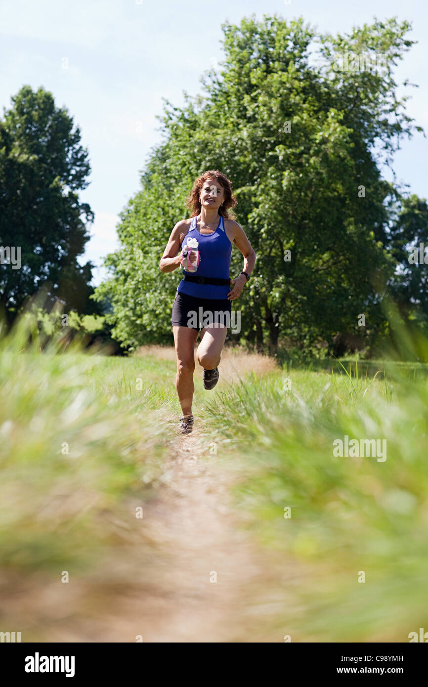 Woman running along path with water bottle Stock Photo - Alamy