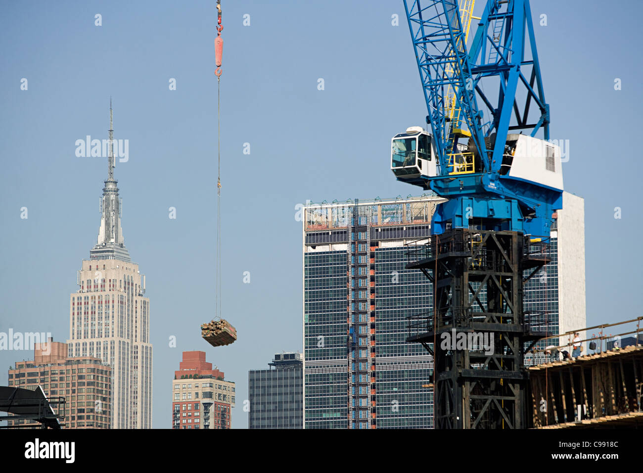 Crane lifting construction material over New York Stock Photo - Alamy