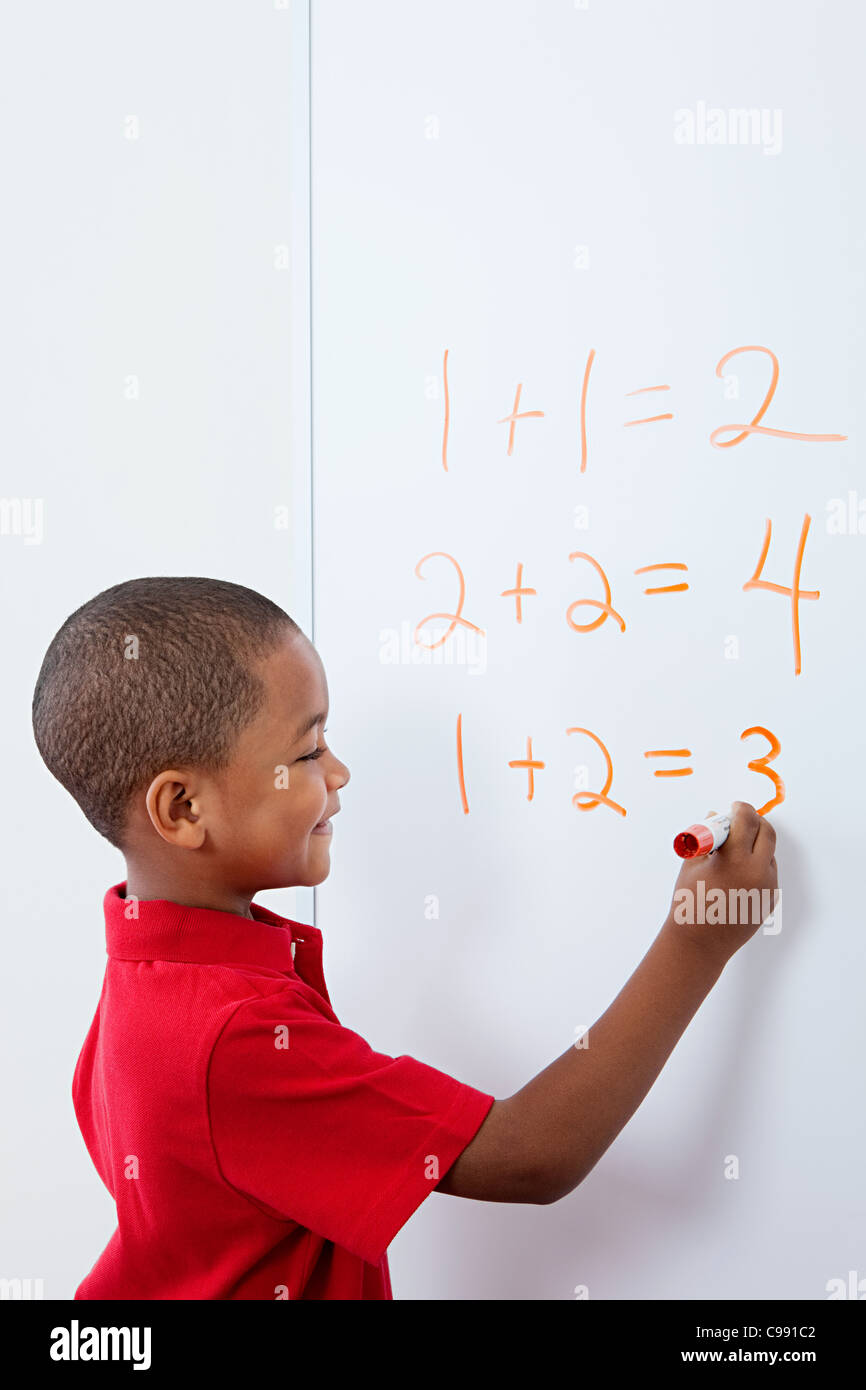 Boy writing answers to sums on whiteboard Stock Photo - Alamy