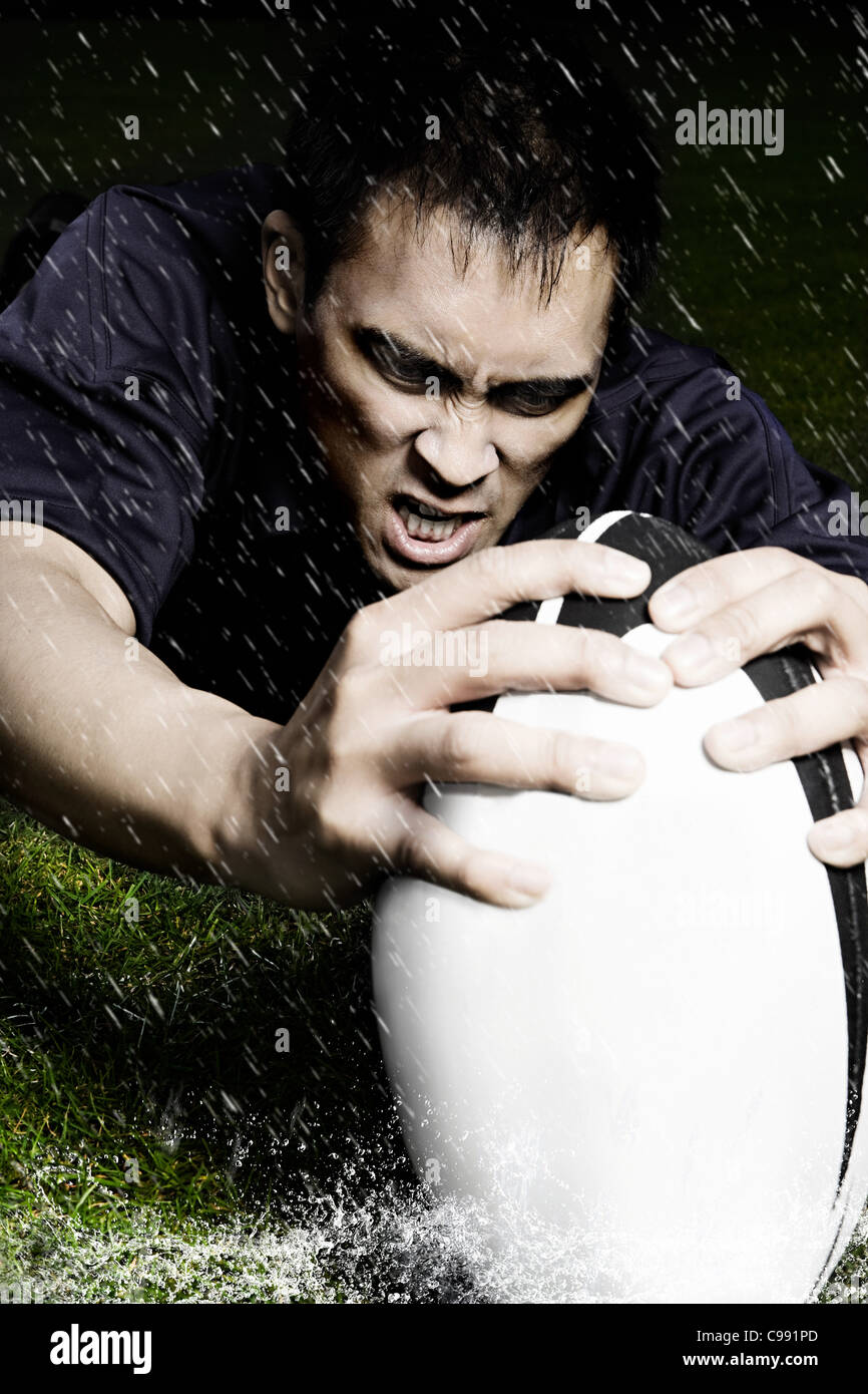 Rugby player with ball in the rain Stock Photo - Alamy