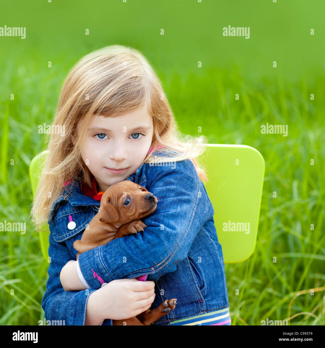 Blond kid girl with puppy pet dog sit in outdoor green grass Stock ...