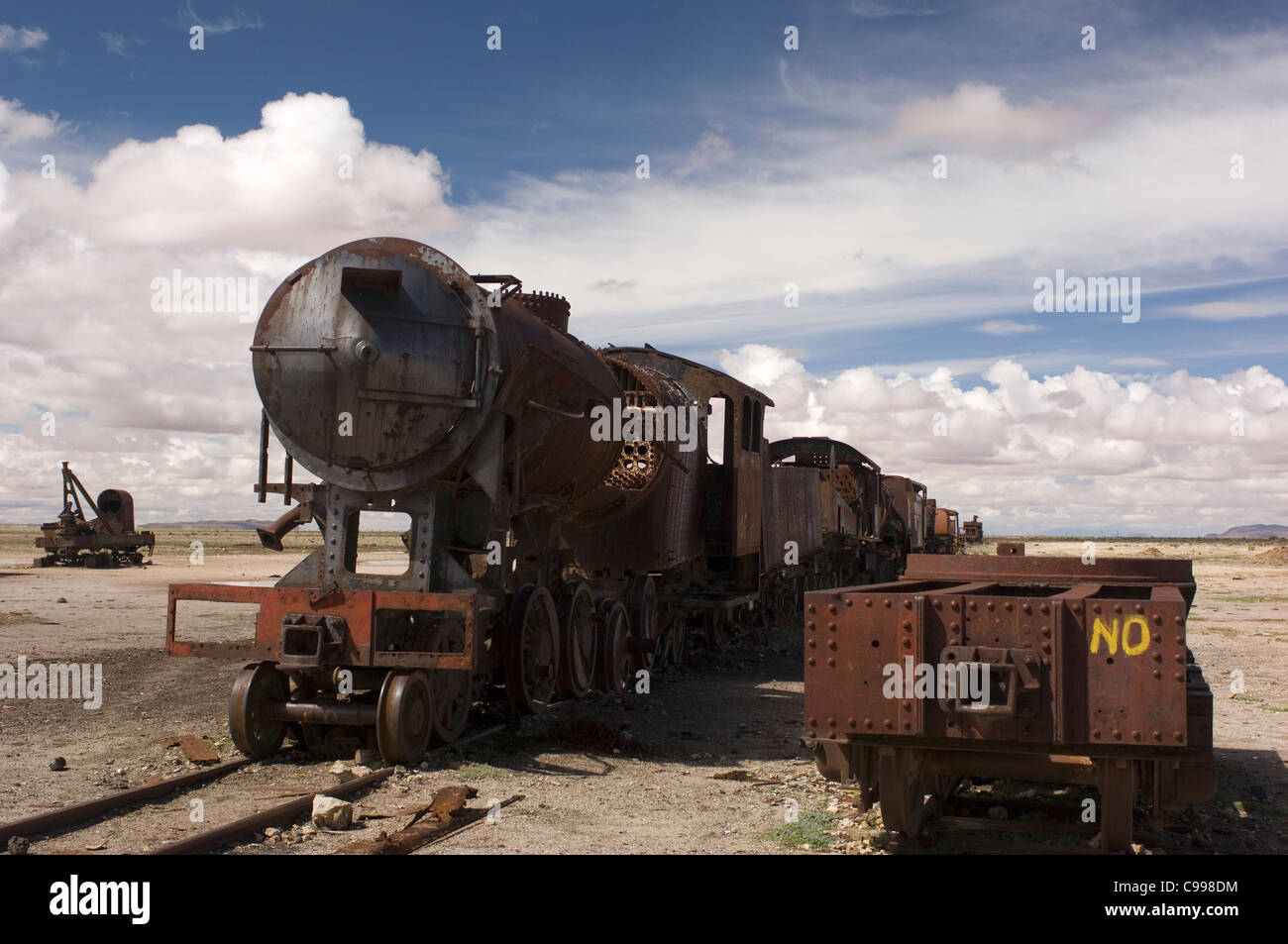 Dozens of old steam locomotives and tenders lie rusting in a desert ...