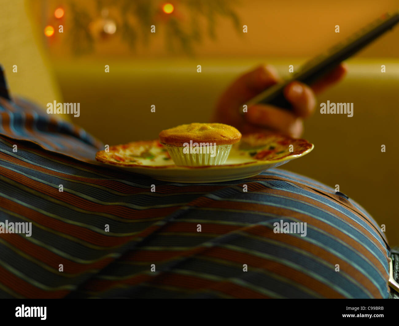 Man with cake on stomach watching TV with remote in hand Stock Photo ...