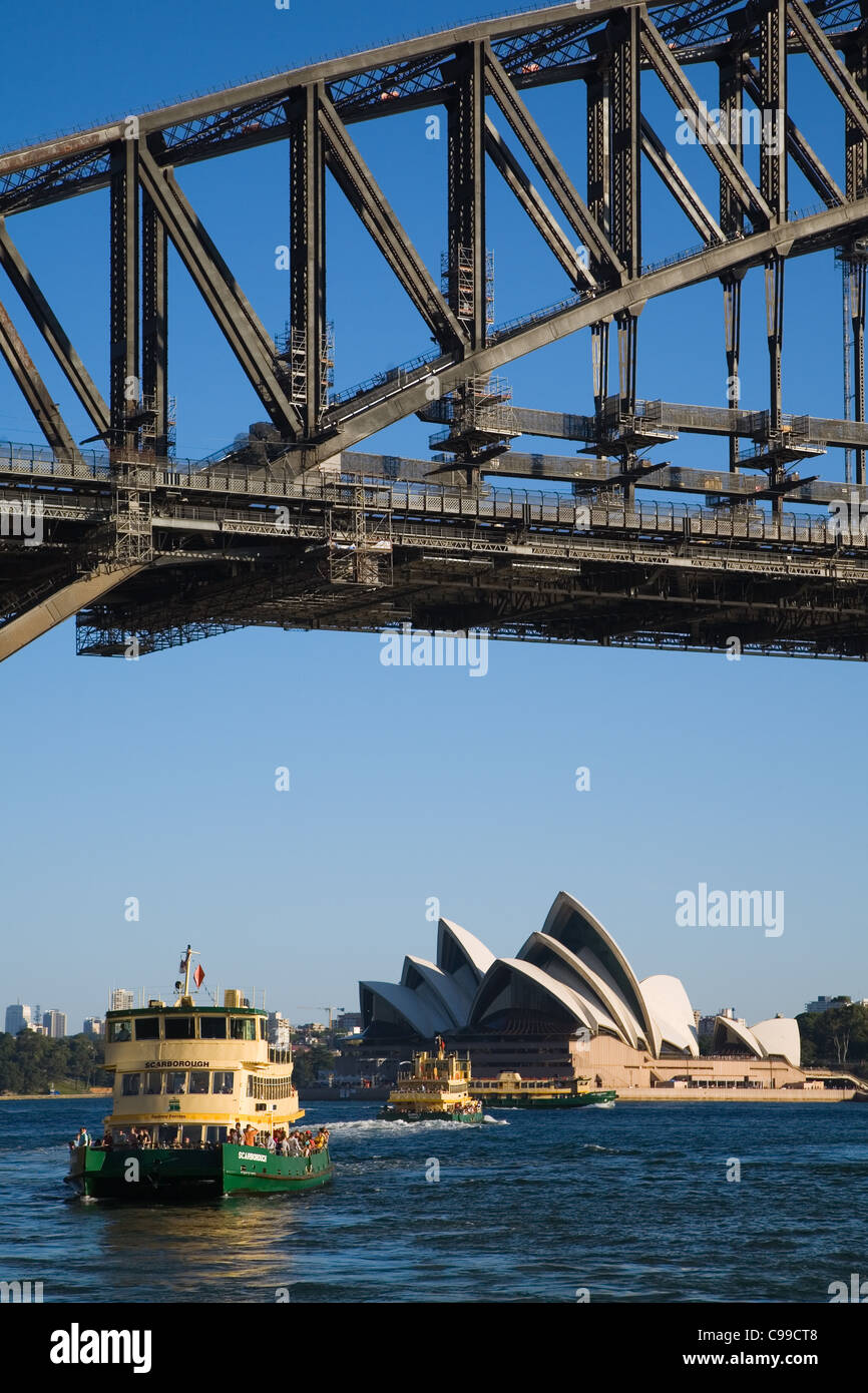 A Sydney ferry cruises under the Harbour Bridge with the Opera House ...