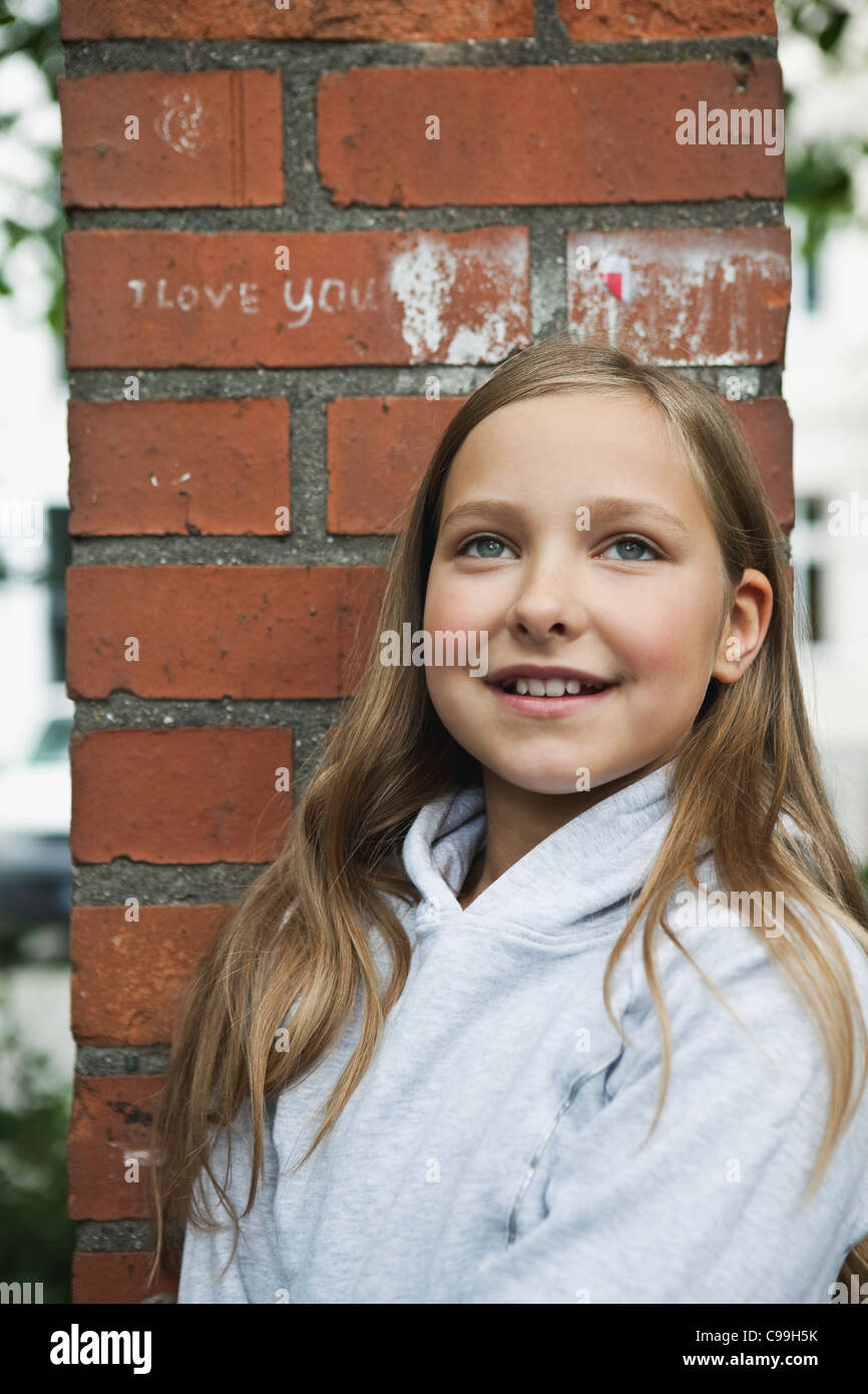 Germany, Berlin, Girl sitting in front of red brick wall Stock Photo ...