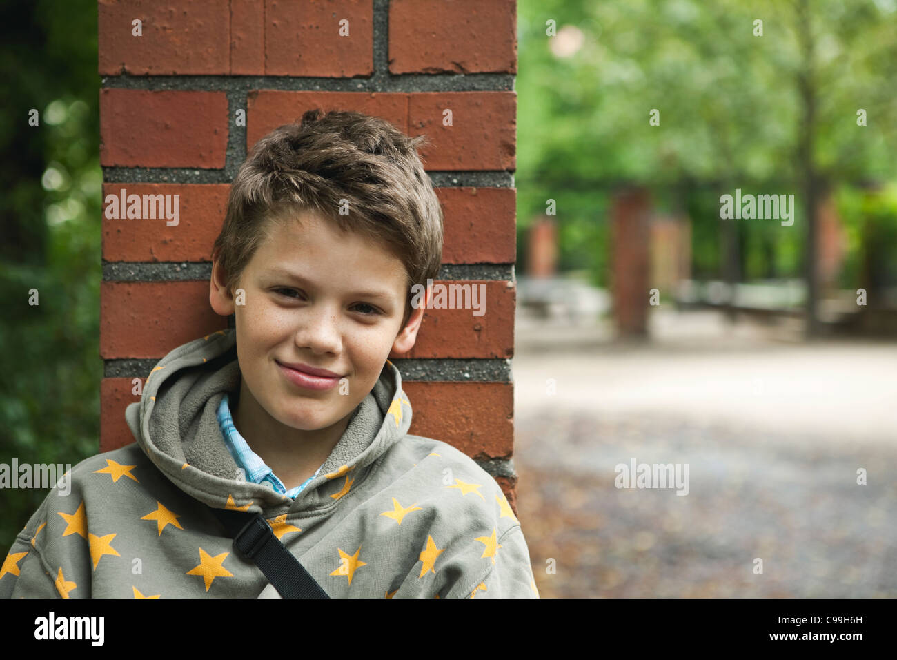 Germany, Berlin, Boy sitting in front of red brick wall Stock Photo - Alamy