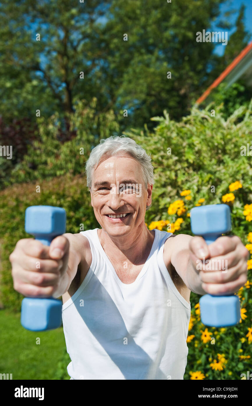 Germany, Bavaria, Mature man doing exercise with dumbbells Stock Photo ...
