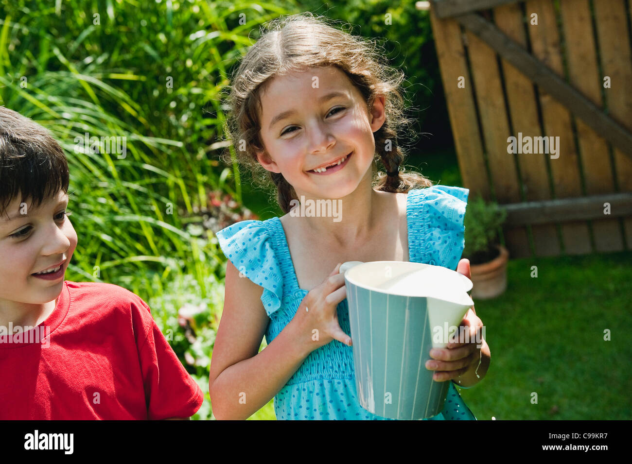 Germany, Bavaria, Girl holding pitcher with boy smiling Stock Photo - Alamy