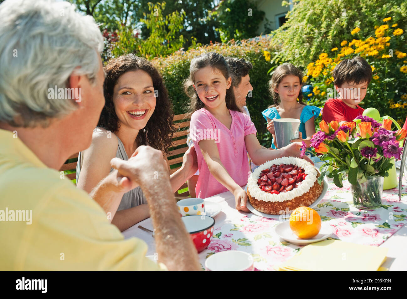 Germany, Bavaria, Family having coffee and cake in garden, smiling ...