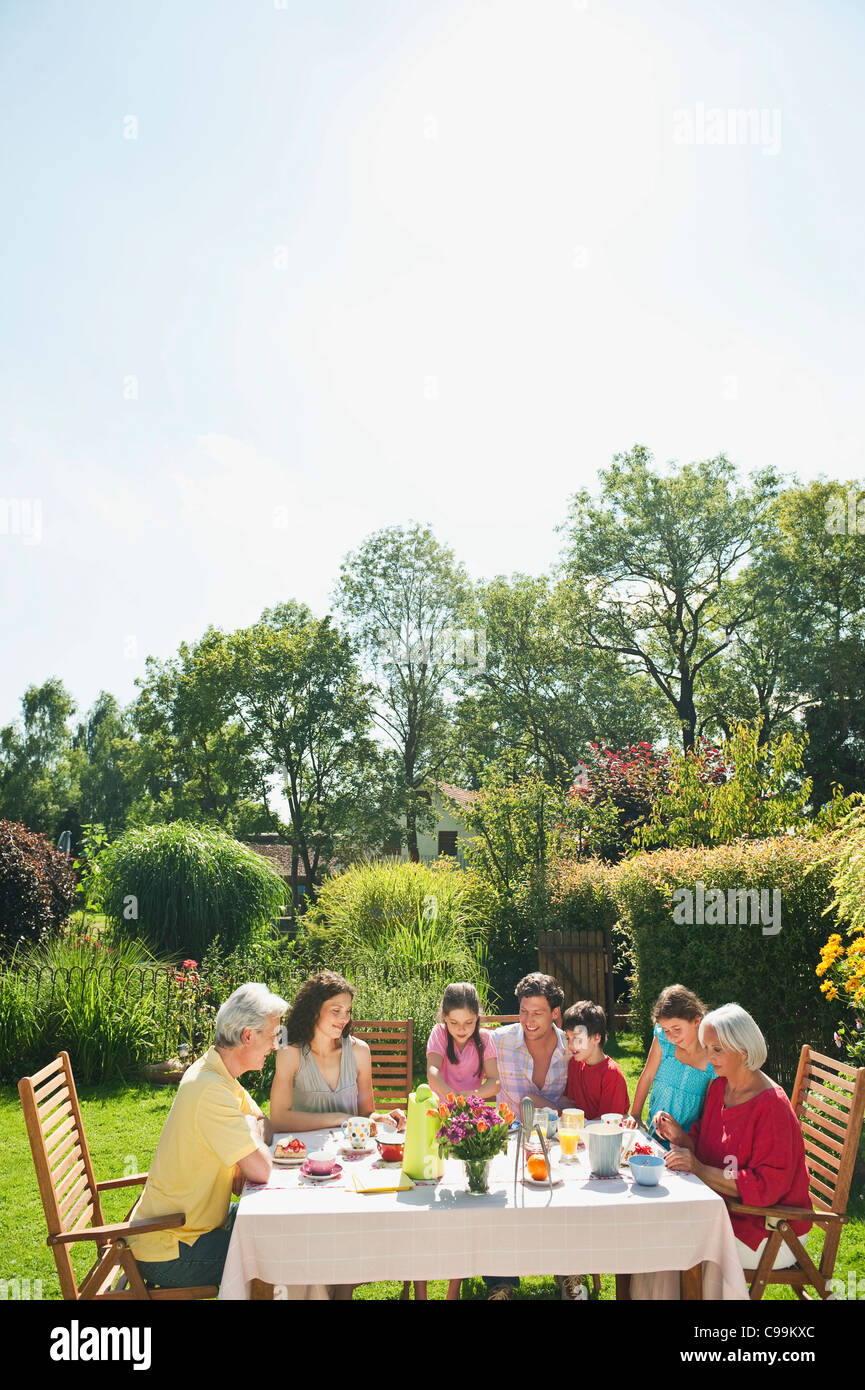 Germany, Bavaria, Family having coffee and cake in garden, smiling ...