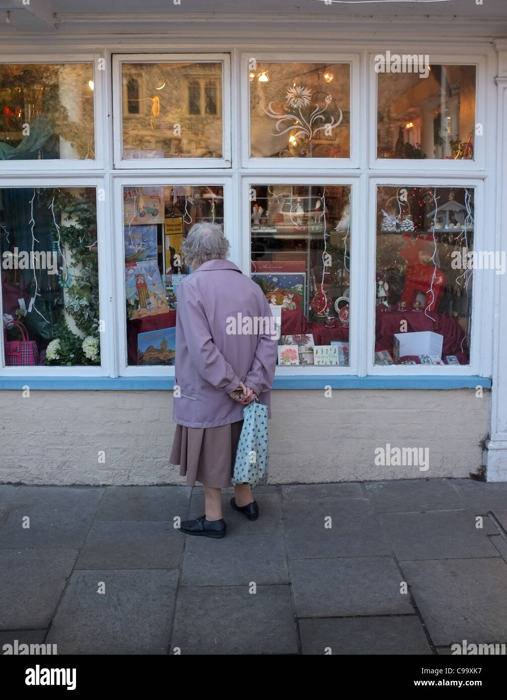 an Old lady looks into a shop window with xmas decorations in ...