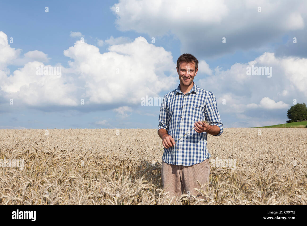 Germany, Bavaria, Altenthann, Man standing in wheat field, smiling ...