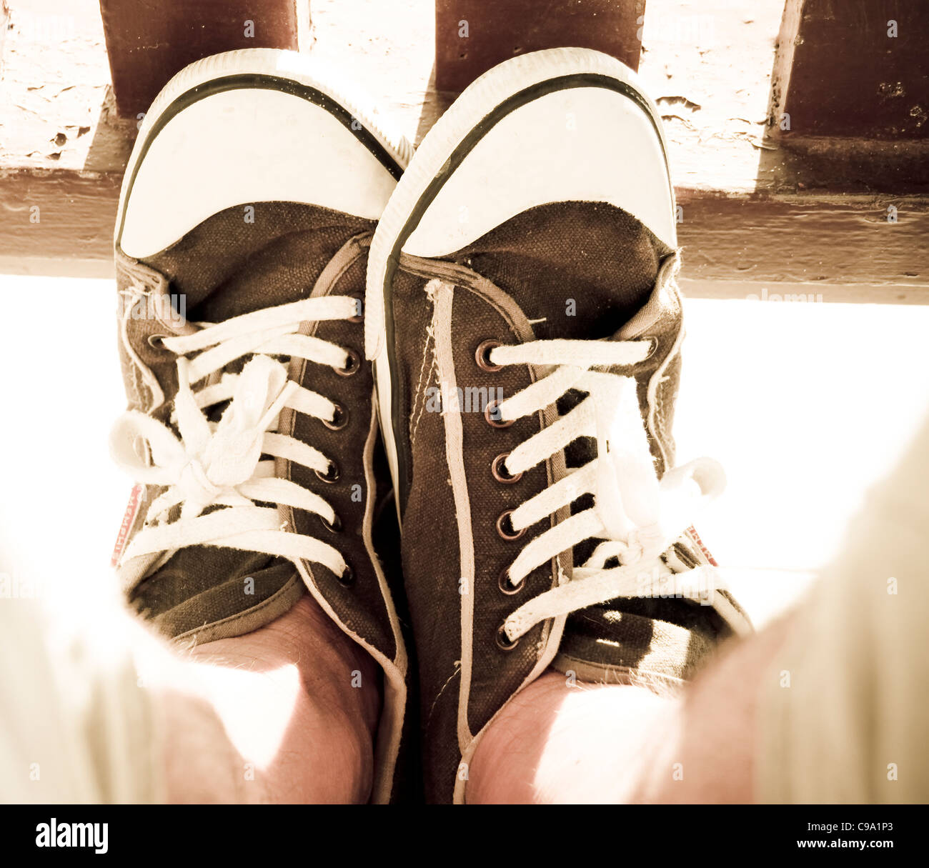 Male feet with scruffy trainers in sunshine Stock Photo - Alamy