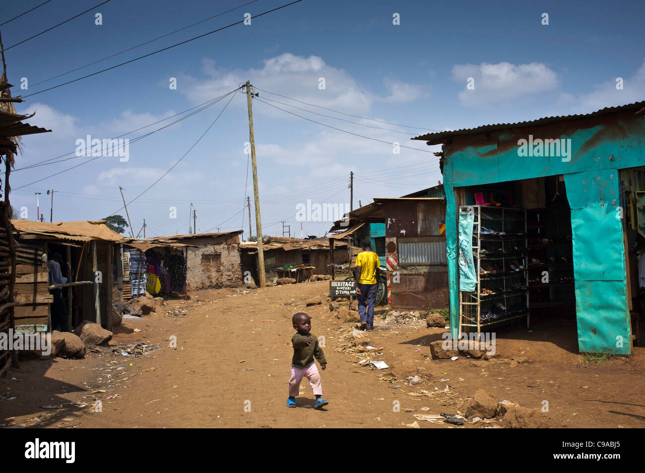 A young boy walks across the street in the Kiandutu slum, Thika, Kenya ...