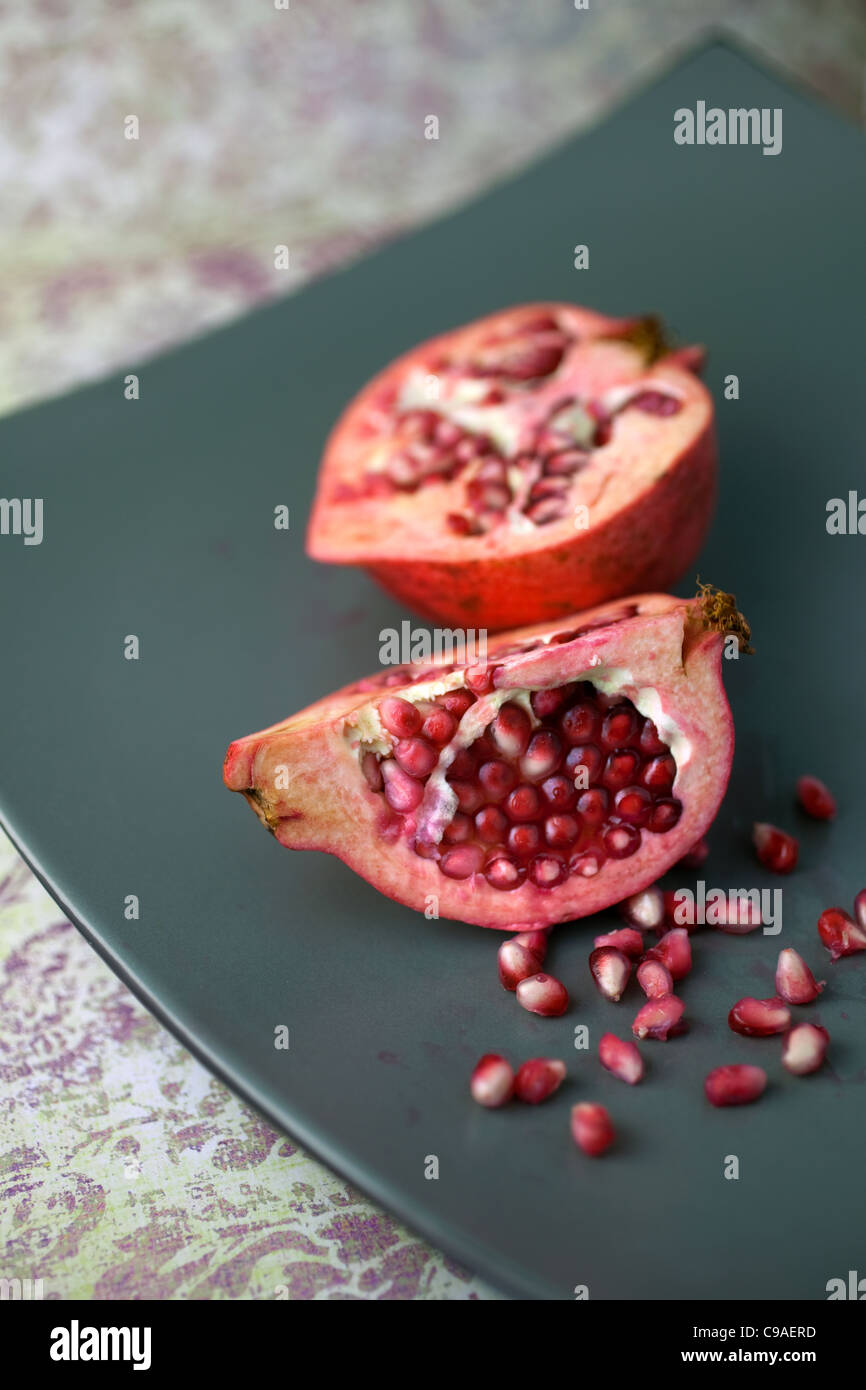 A pomegranate split open to display its red juicy seeds Stock Photo - Alamy