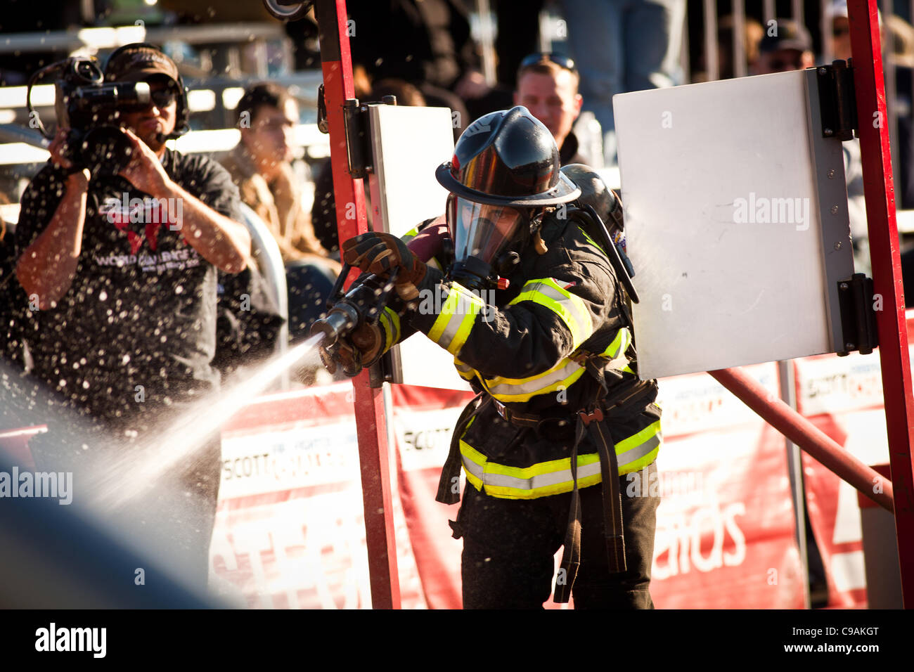 A firefighter aims a firehose at a target while wearing full ...
