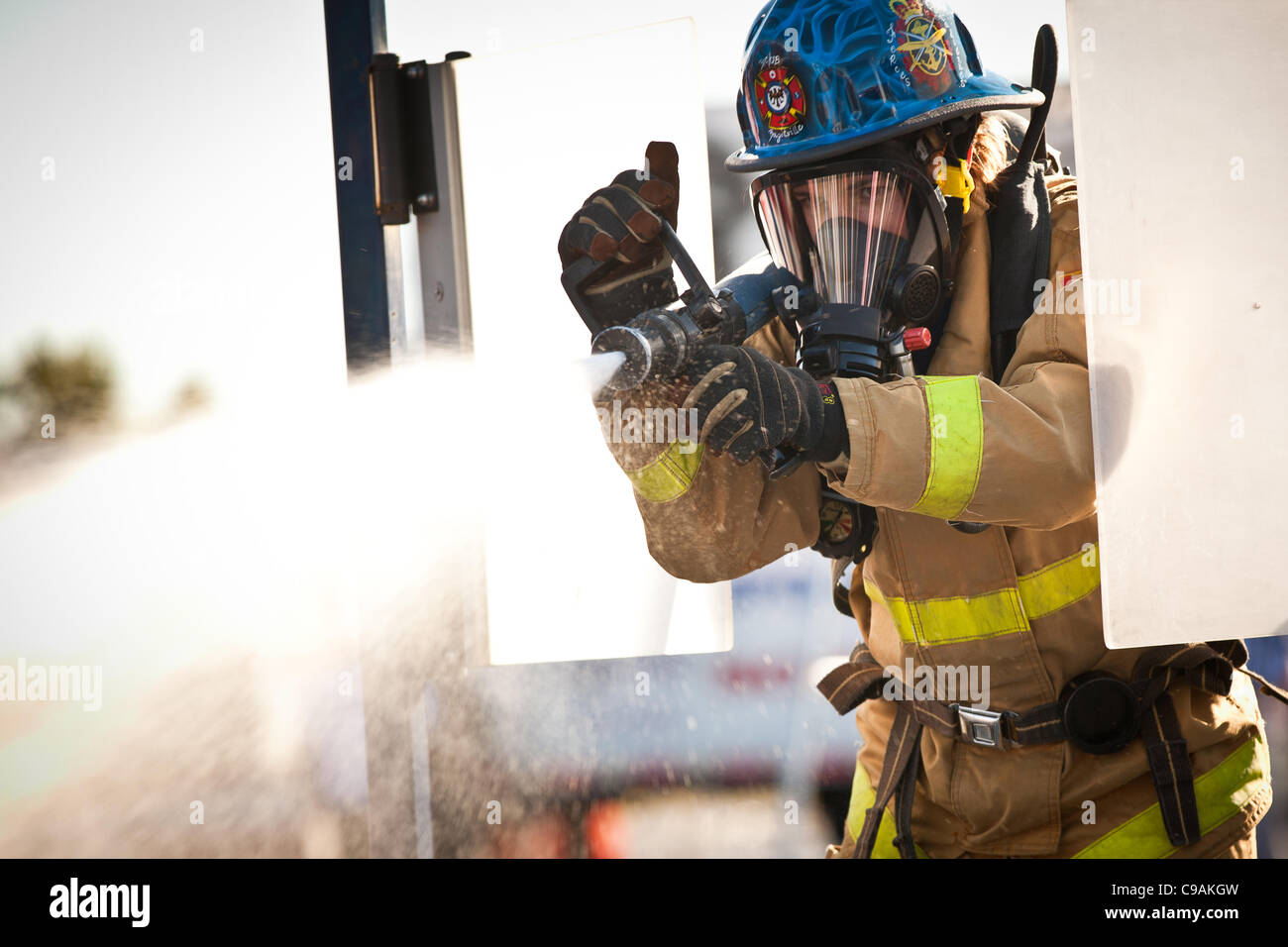 A firefighter aims a firehose at a target while wearing full ...