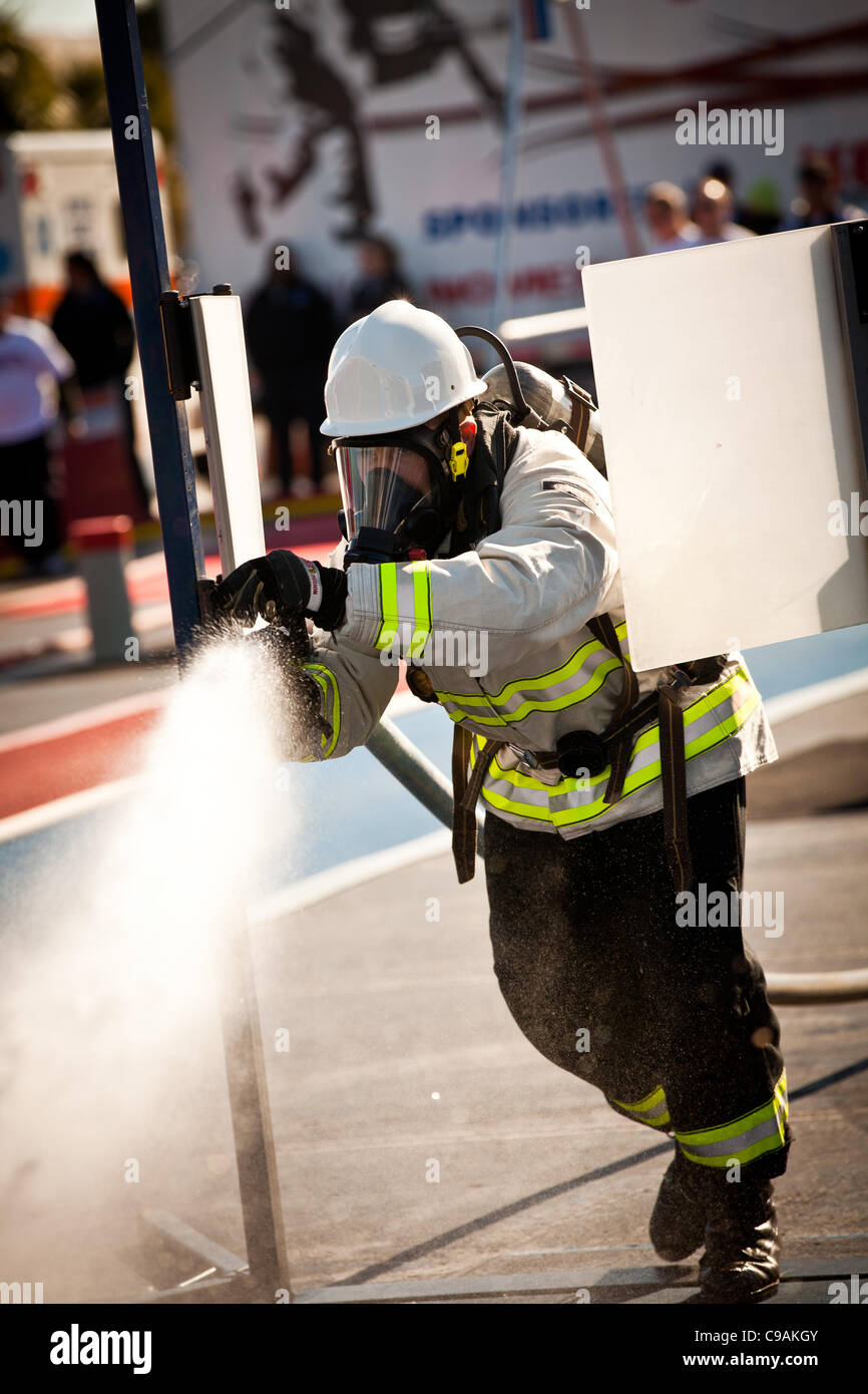 A firefighter aims a firehose at a target while wearing full ...