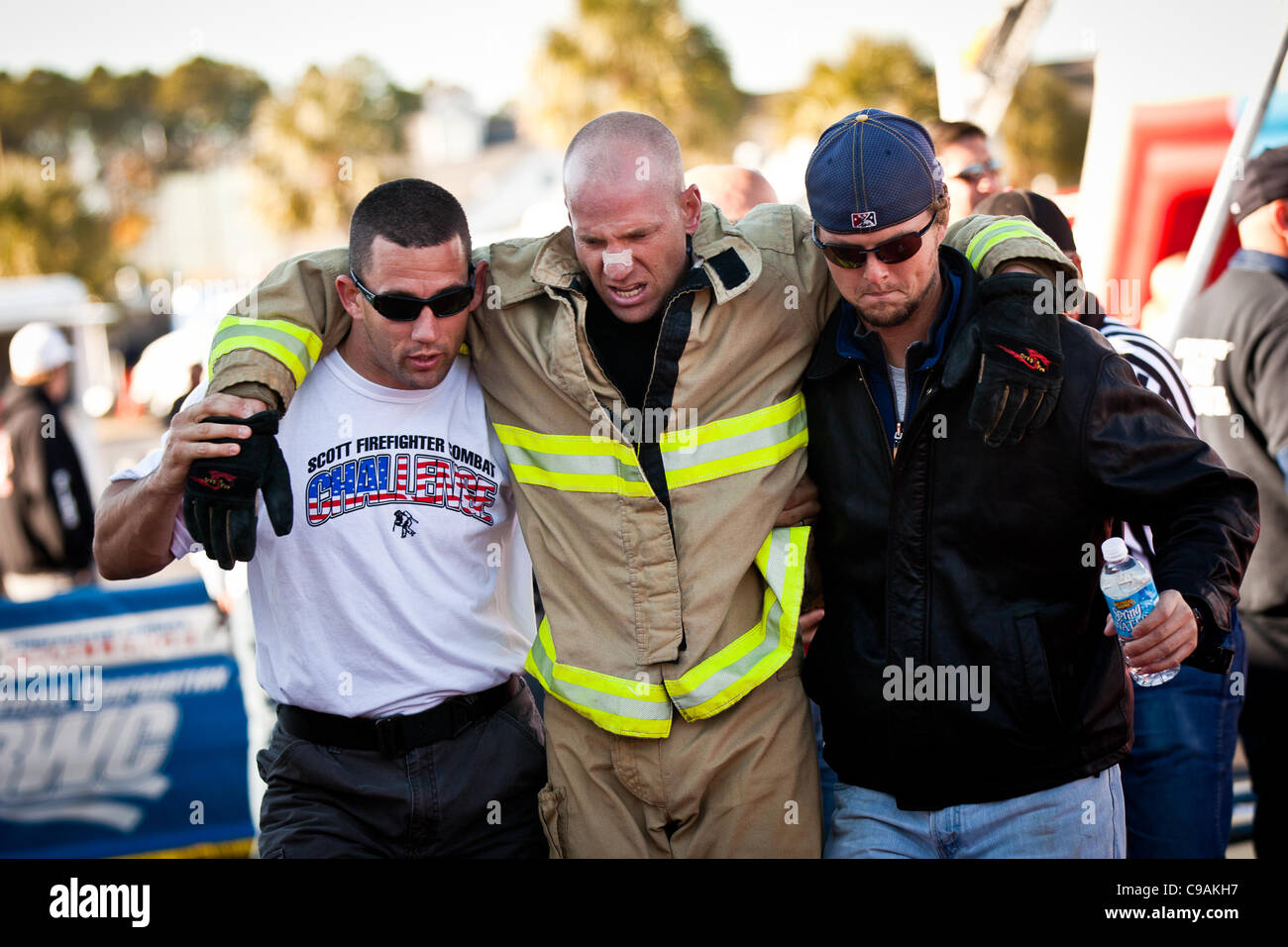An exhausted firefighter is helped by officials after finishing the ...