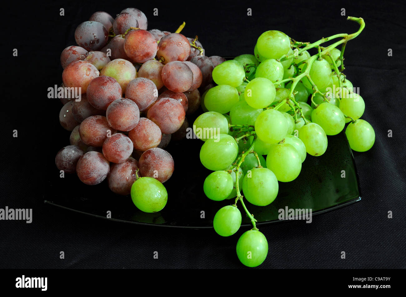 Two bunches of grape on a black plate Stock Photo - Alamy