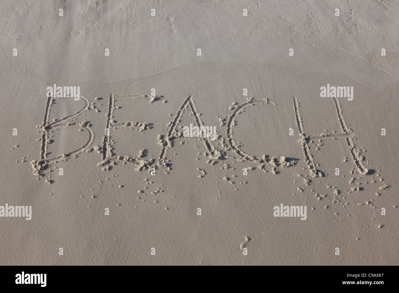 Beach written in sand on the wet beach Stock Photo - Alamy