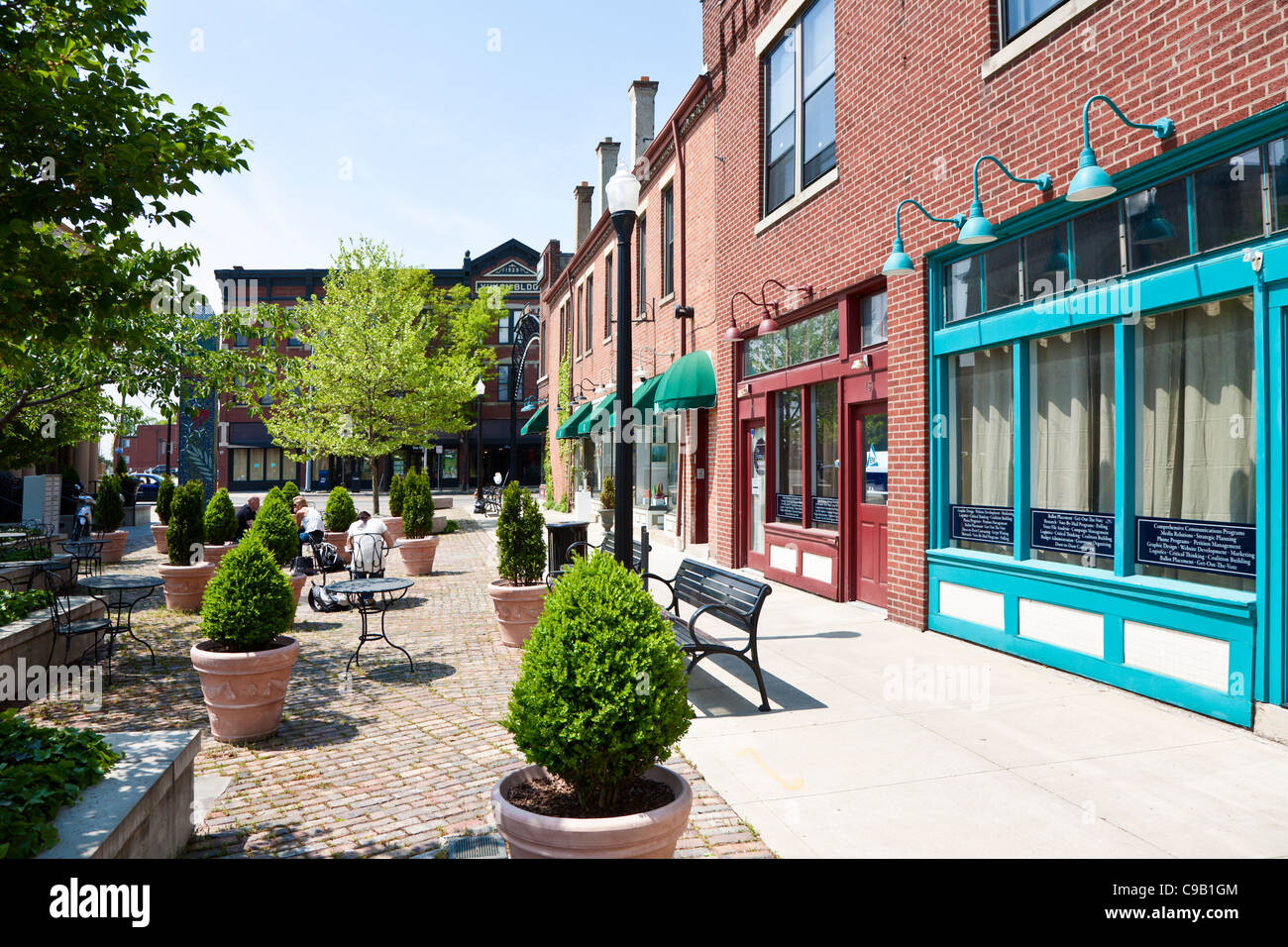 People enjoy the spring weather on a patio between buildings in the ...