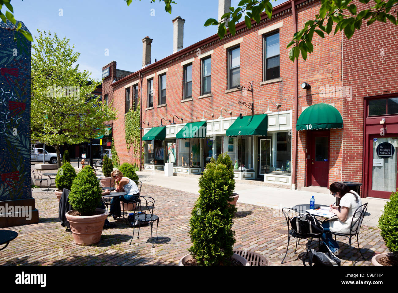 People enjoy the spring weather on a patio between buildings in the ...