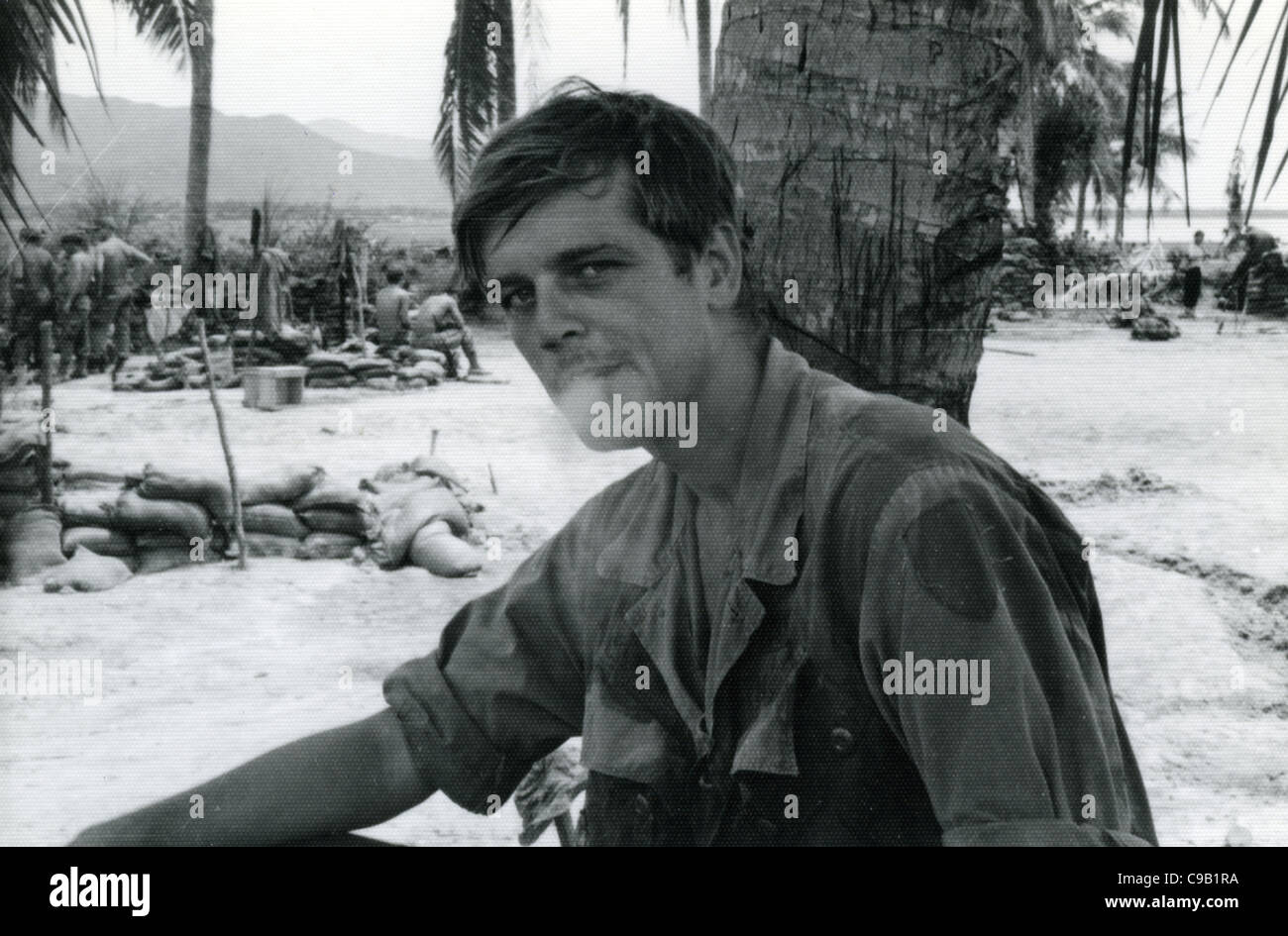 solider exhaling cigarette smoke while resting under palm tree. 101st ...