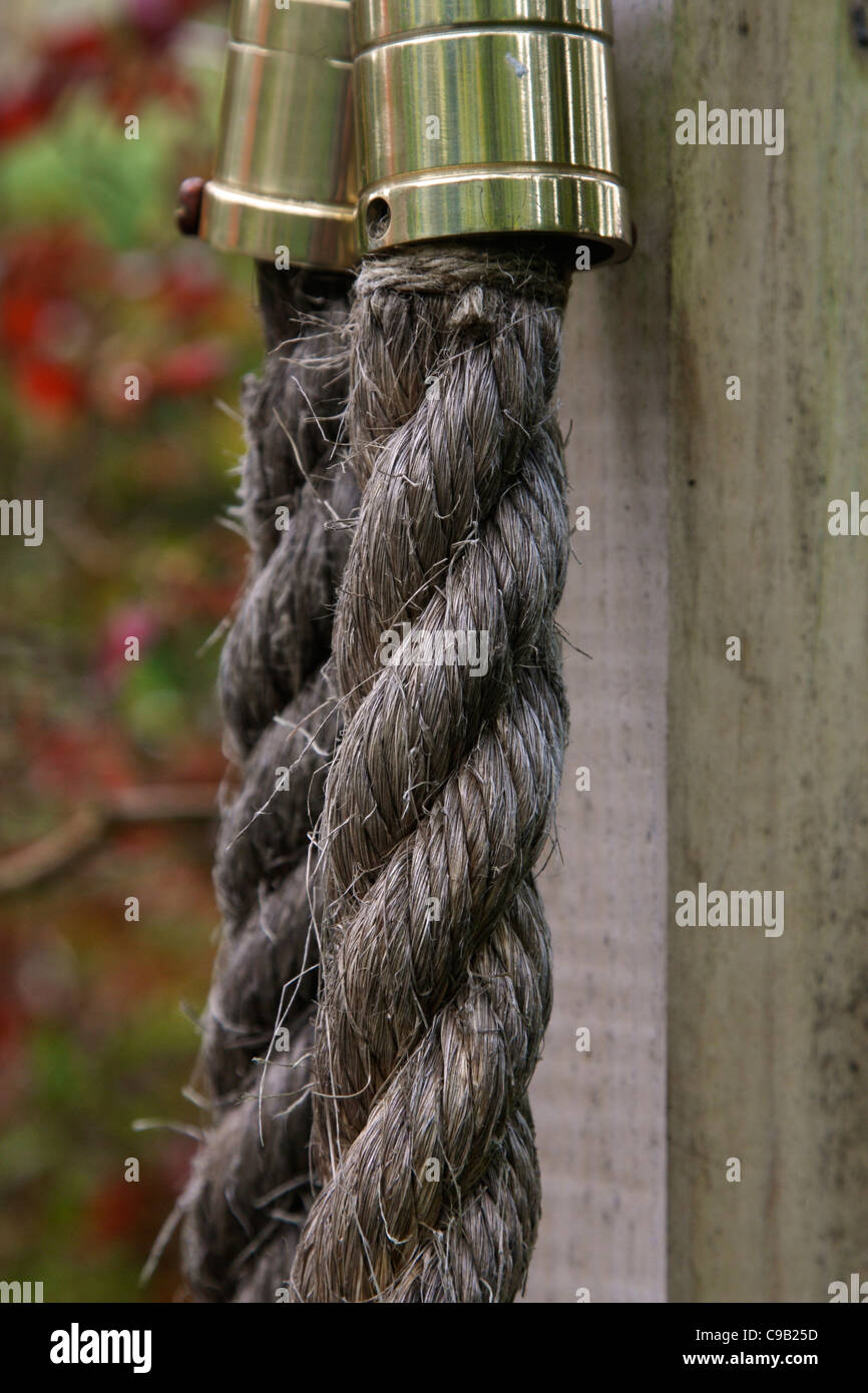 Detail shot of rope and wooden fence post. Blurred green and red ...