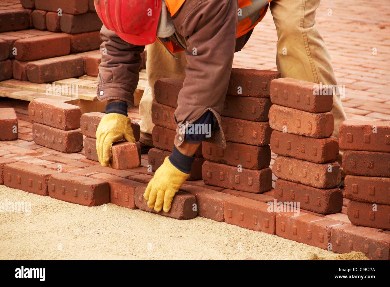A construction worker lays paving bricks during Marion Street ...