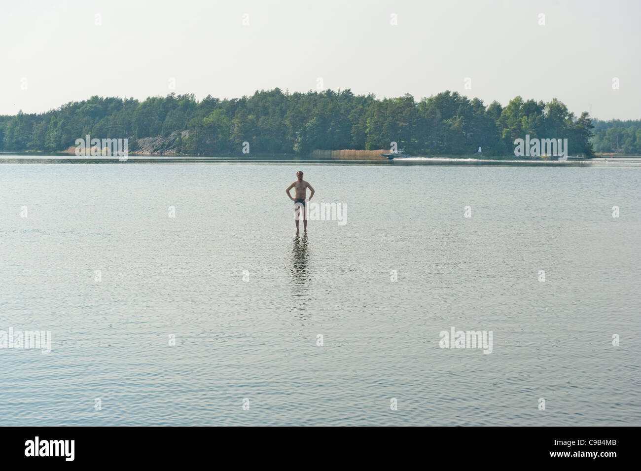 A man standing in the shallows of water, Korppoo Island Turku ...
