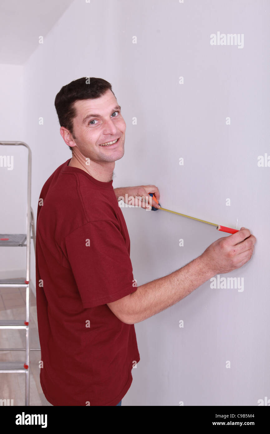 Man measuring wall with tape measure Stock Photo - Alamy