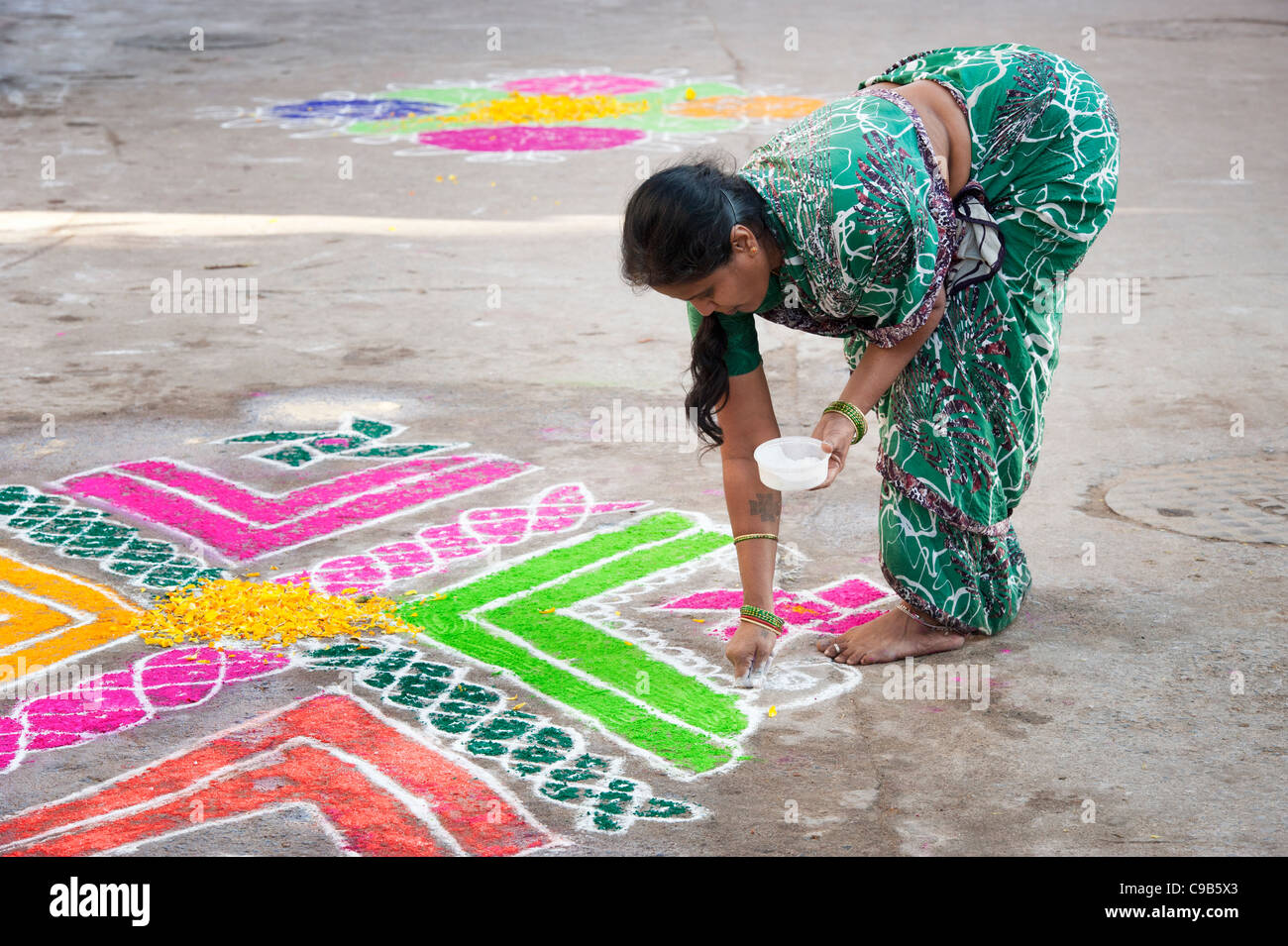 India woman making a Rangoli dasara festival design in an Indian street ...