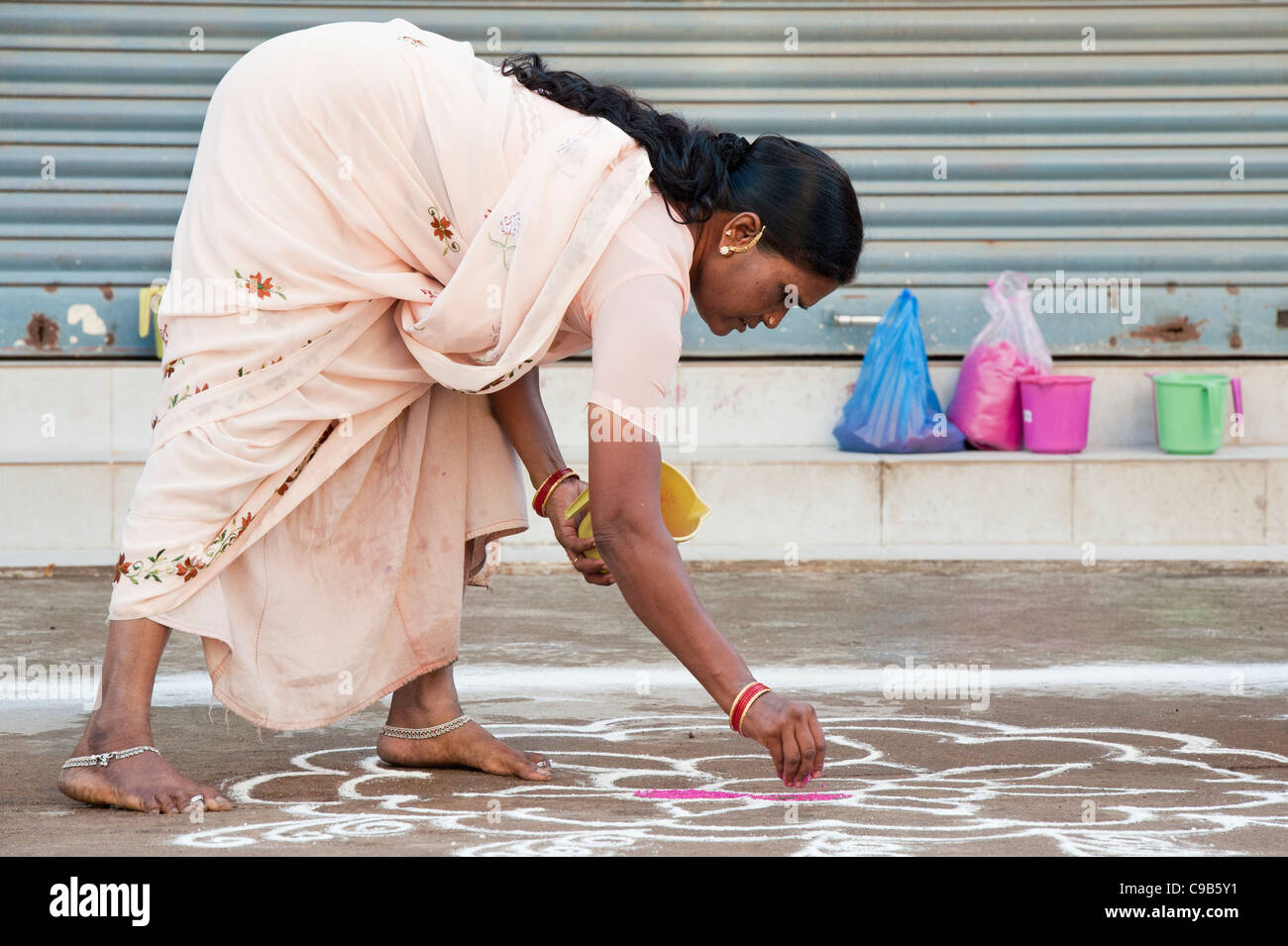 India woman making a Rangoli dasara festival design in an Indian street ...
