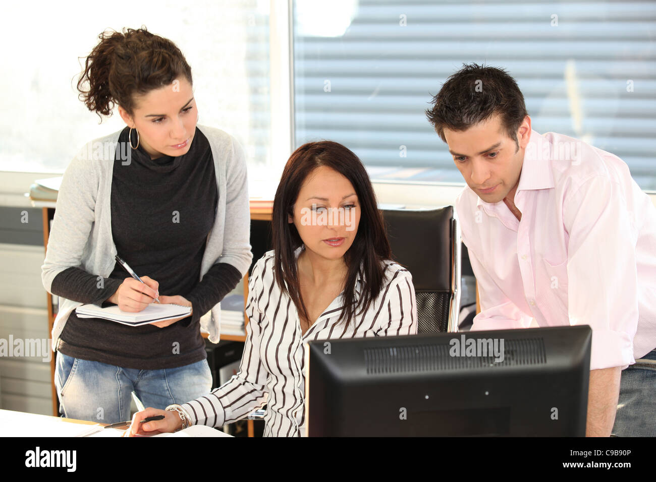 People looking at a computer in an office Stock Photo - Alamy