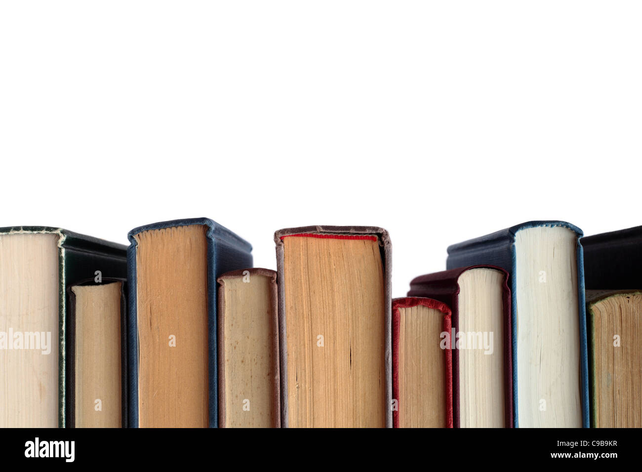 A line of hardback books, both old and new, with a white background ...