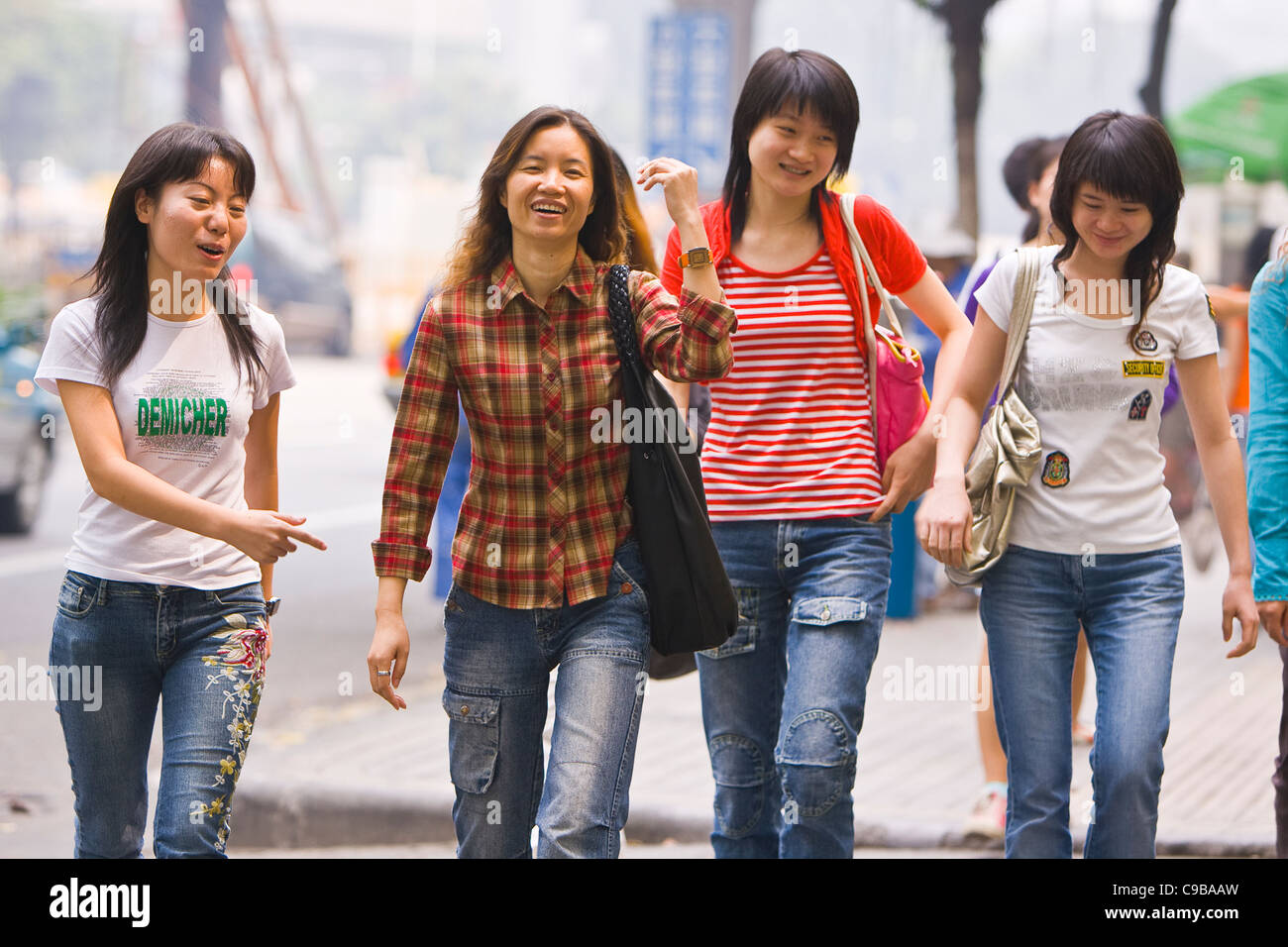 GUANGZHOU, GUANGDONG PROVINCE, CHINA - Young women walking on sidewalk ...