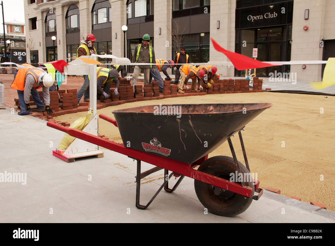 Wheelbarrow and onstruction workers lay paving bricks during Marion ...