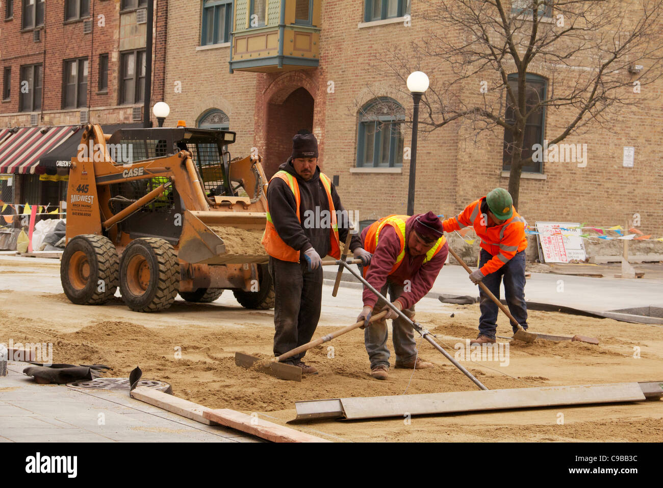 Construction workers prepare sand bed for paving bricks during Marion ...